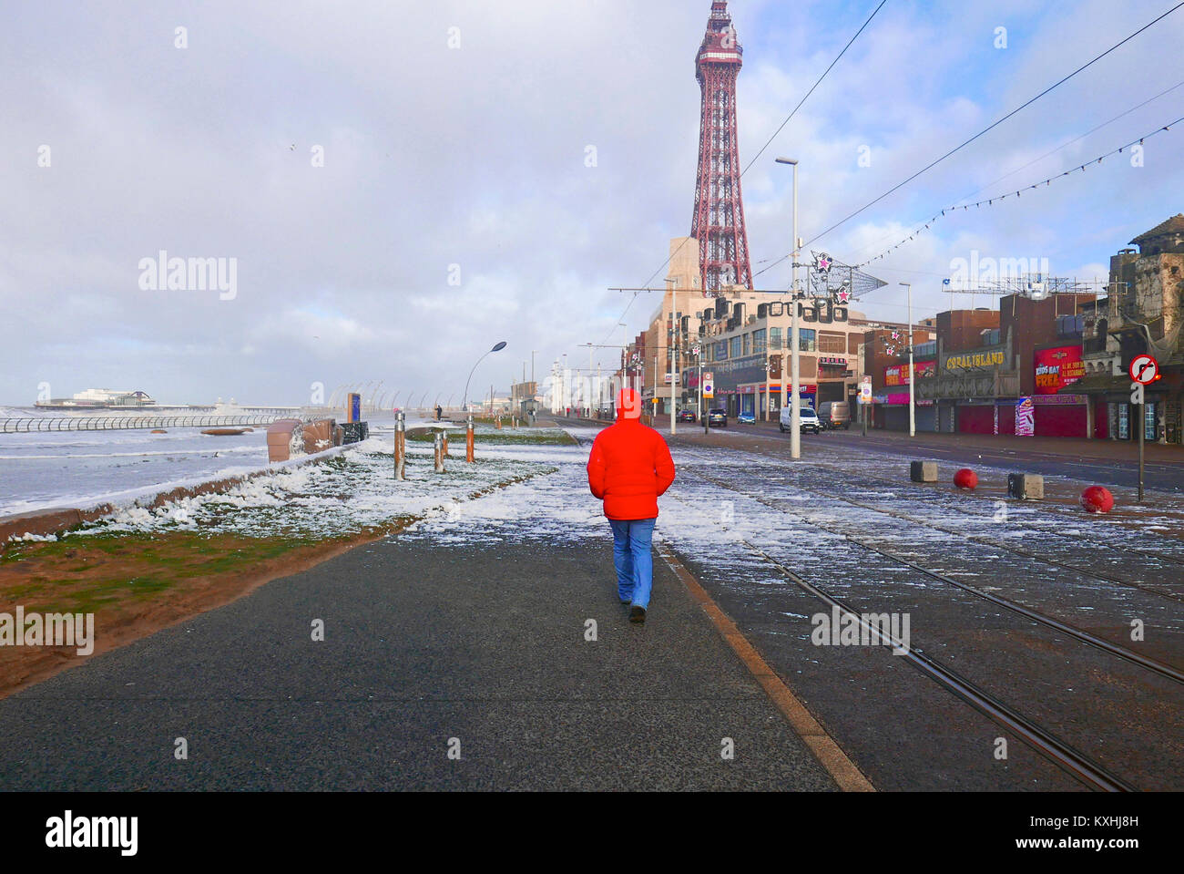 Man in red coat walking along Blackpool seafront during storm Stock ...