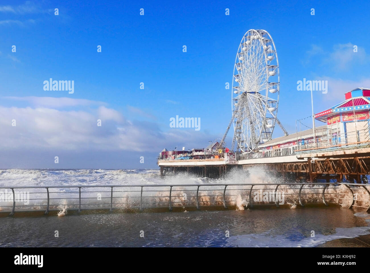 Waves crashing over the seawall in front of the Ferris wheel on Central ...