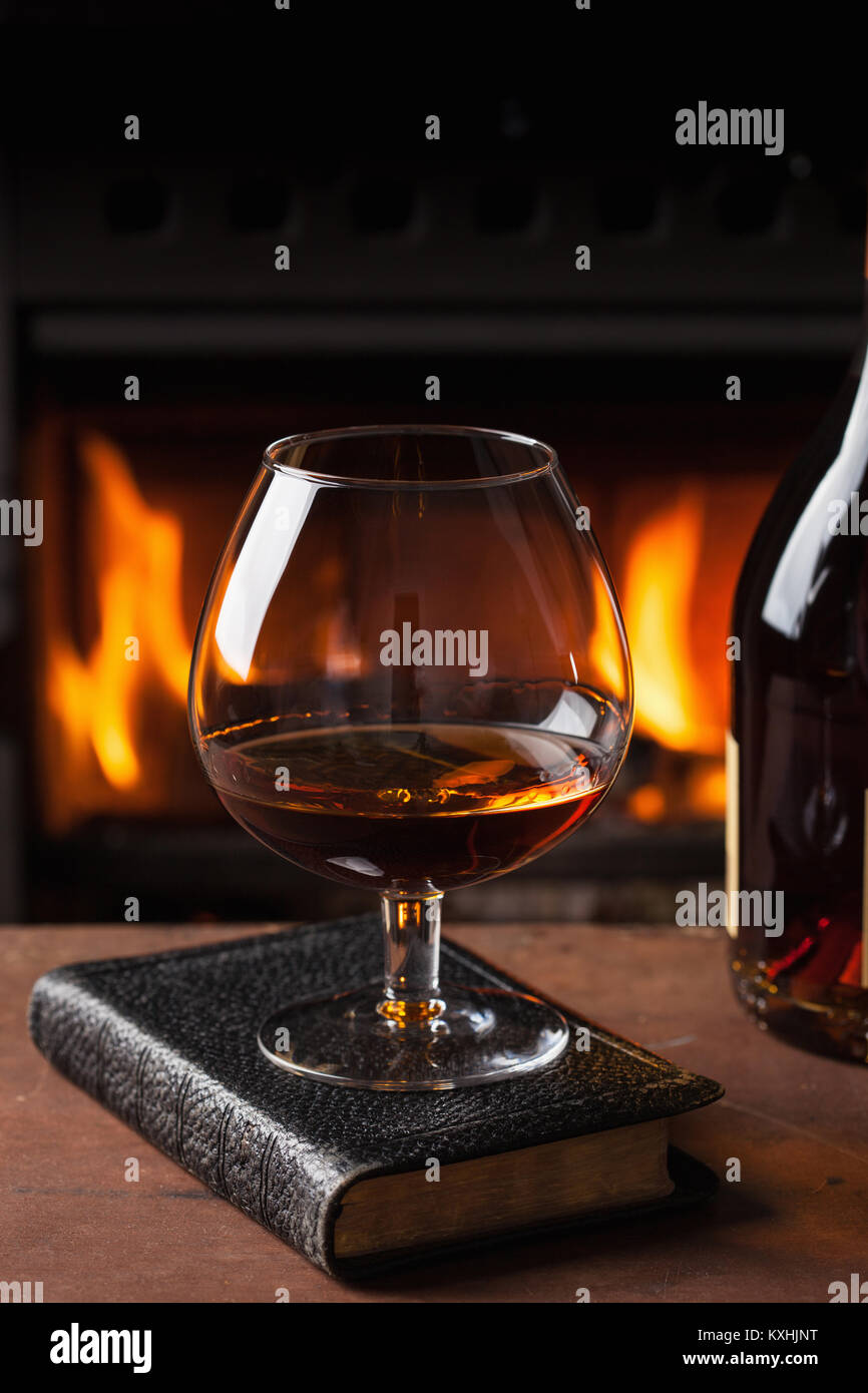 a glass of cognac in front of fireplace Stock Photo - Alamy