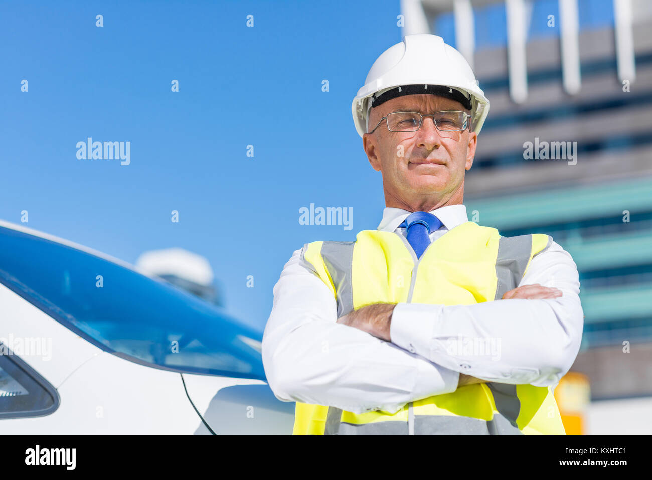Confident construction engineer in hardhat with arms crossed on chest ...