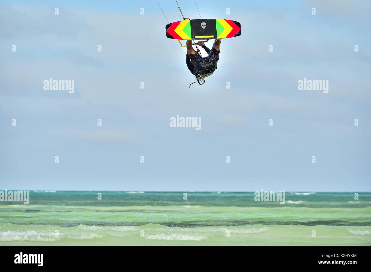 A kitesurfer performing an aerial trick riding strapless surfboard on a ...