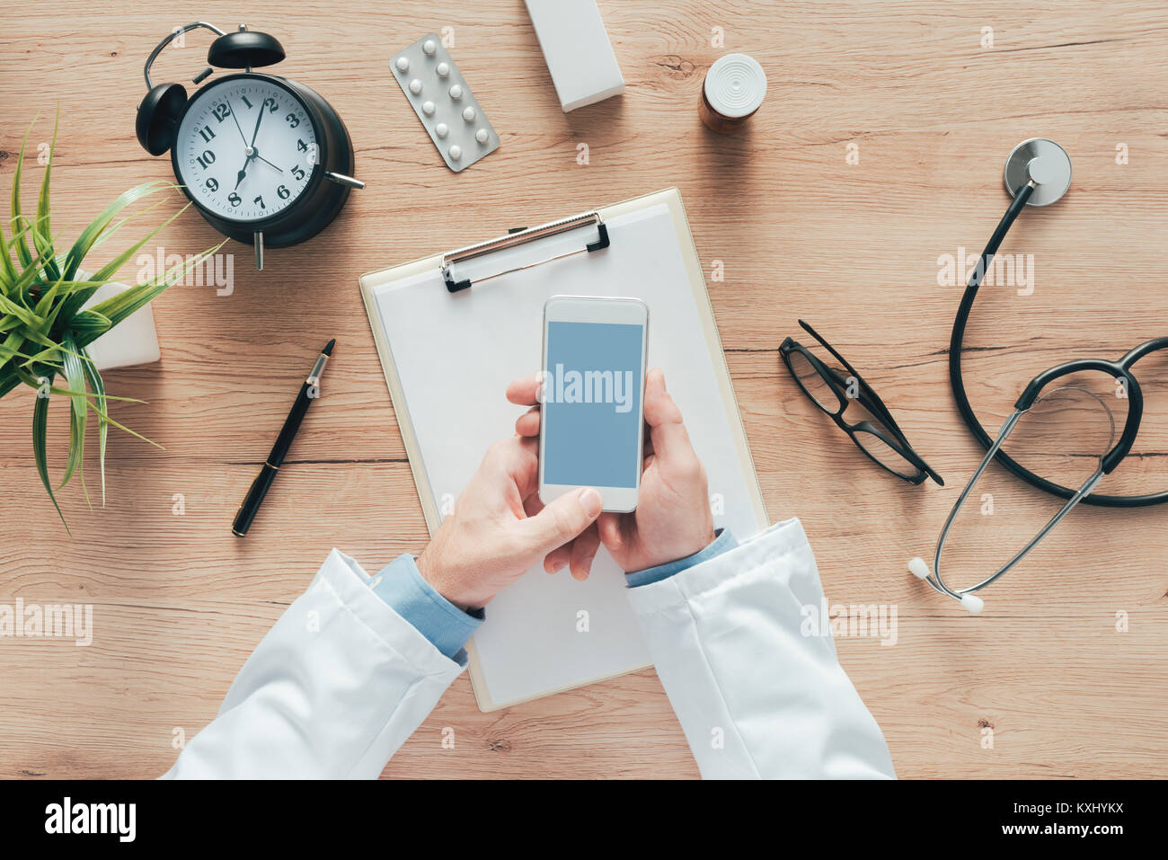 Doctor using smartphone app in hospital office, overhead view of male ...