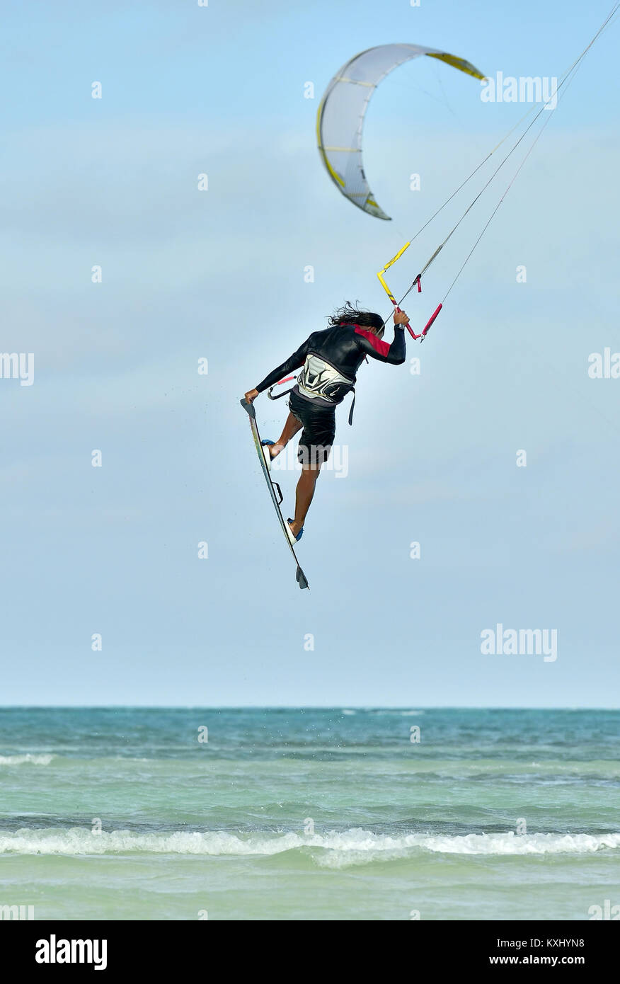 A kitesurfer performing an aerial trick riding strapless surfboard on a ...