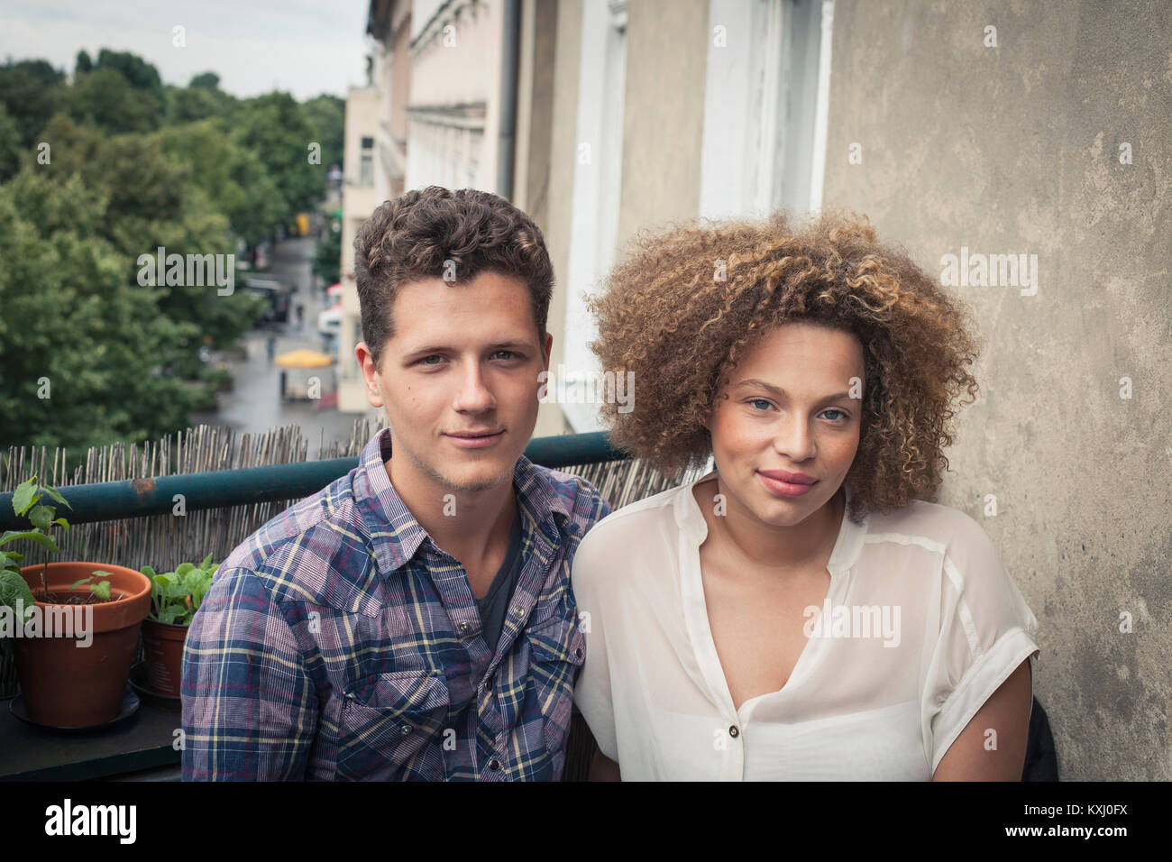 Portrait of smiling friends sitting by wall in balcony Stock Photo - Alamy