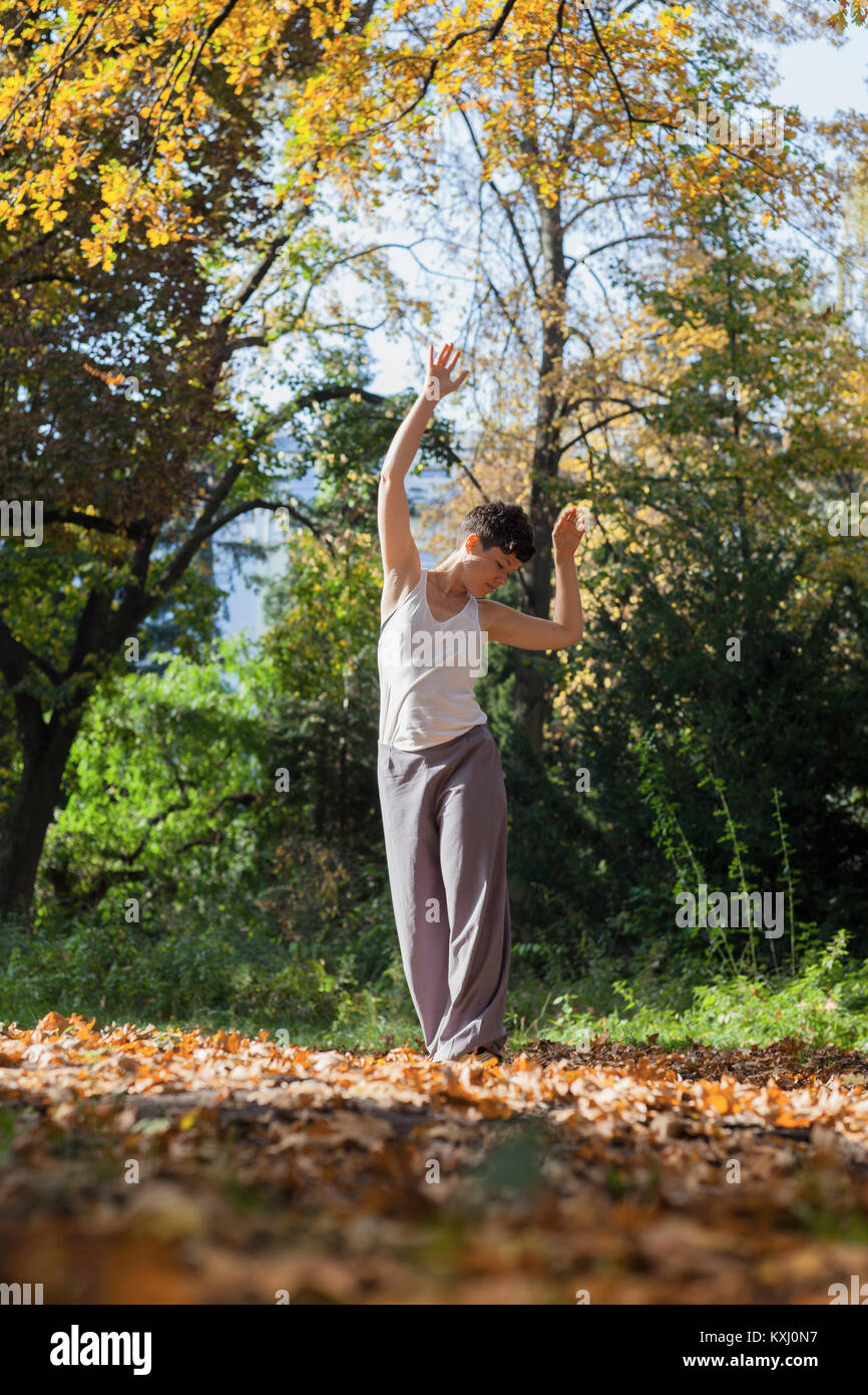 Full length of young woman dancing on field against plants at park ...