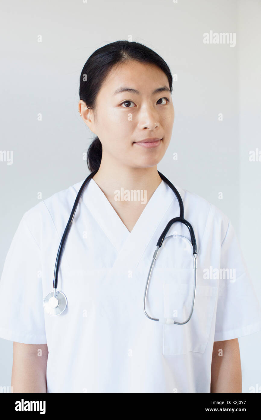 Portrait of confident doctor standing against white wall Stock Photo ...