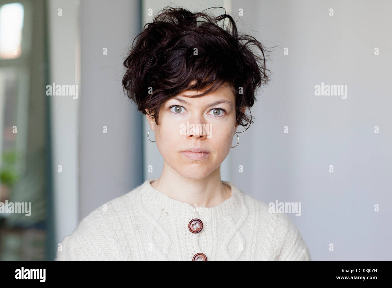 Close-up portrait of frowning woman with short hair against wall Stock ...