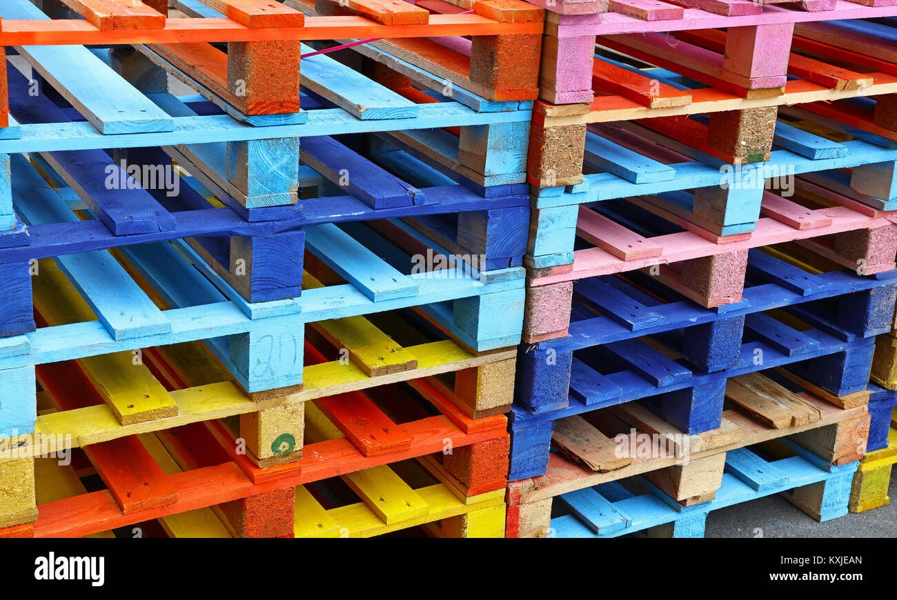 Close up stack of many vivid multicolor painted colorful wooden pallets ...