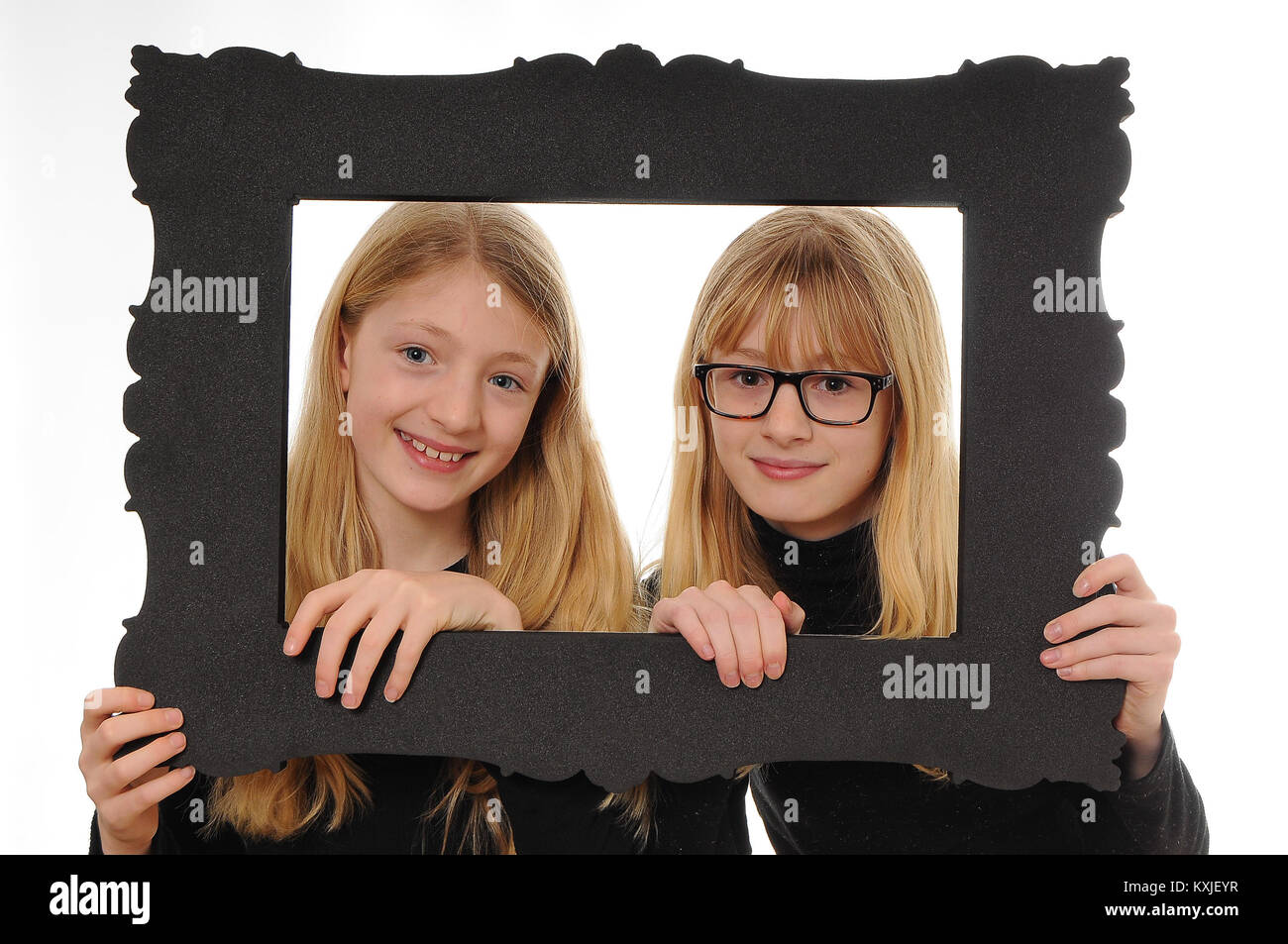 two pretty blonde Caucasian girls, looking through a frame isolated on ...