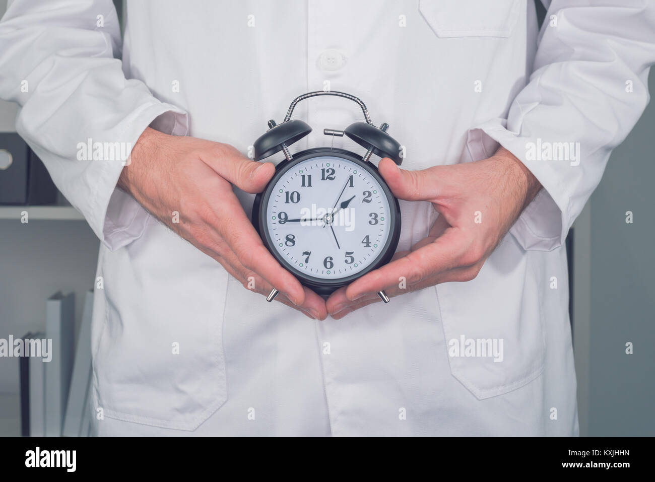 Doctor with alarm clock in hands, it is time to make an appointment for ...