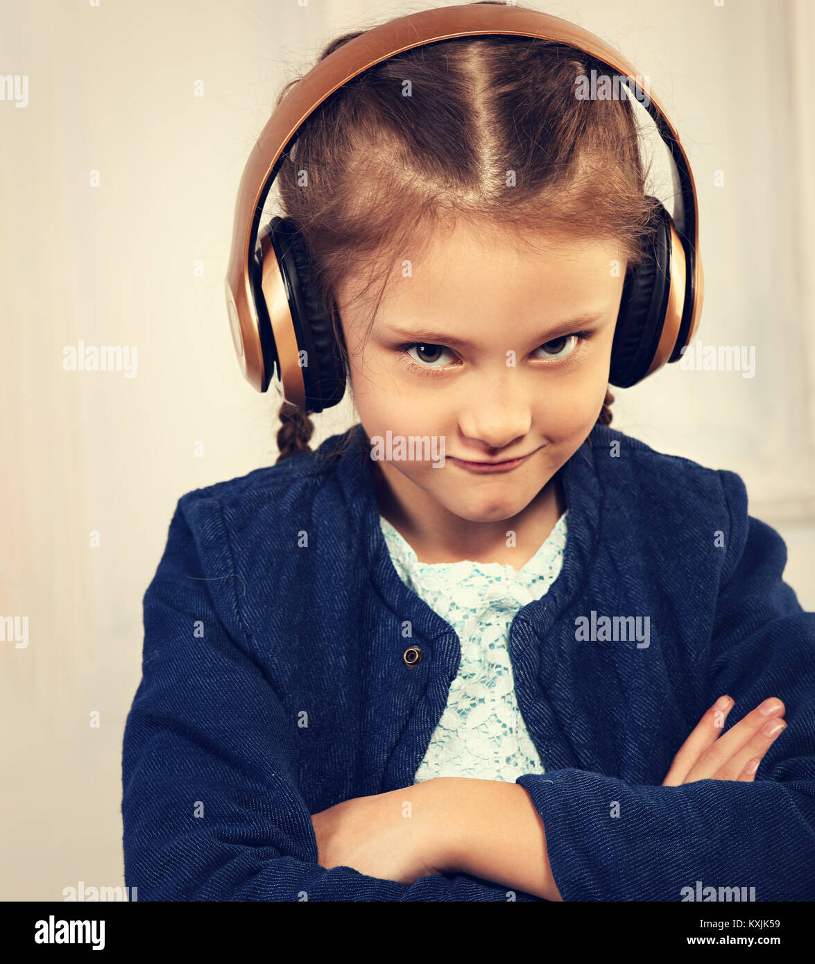 Angry funny serious kid girl in blue jacket listening the music in ...