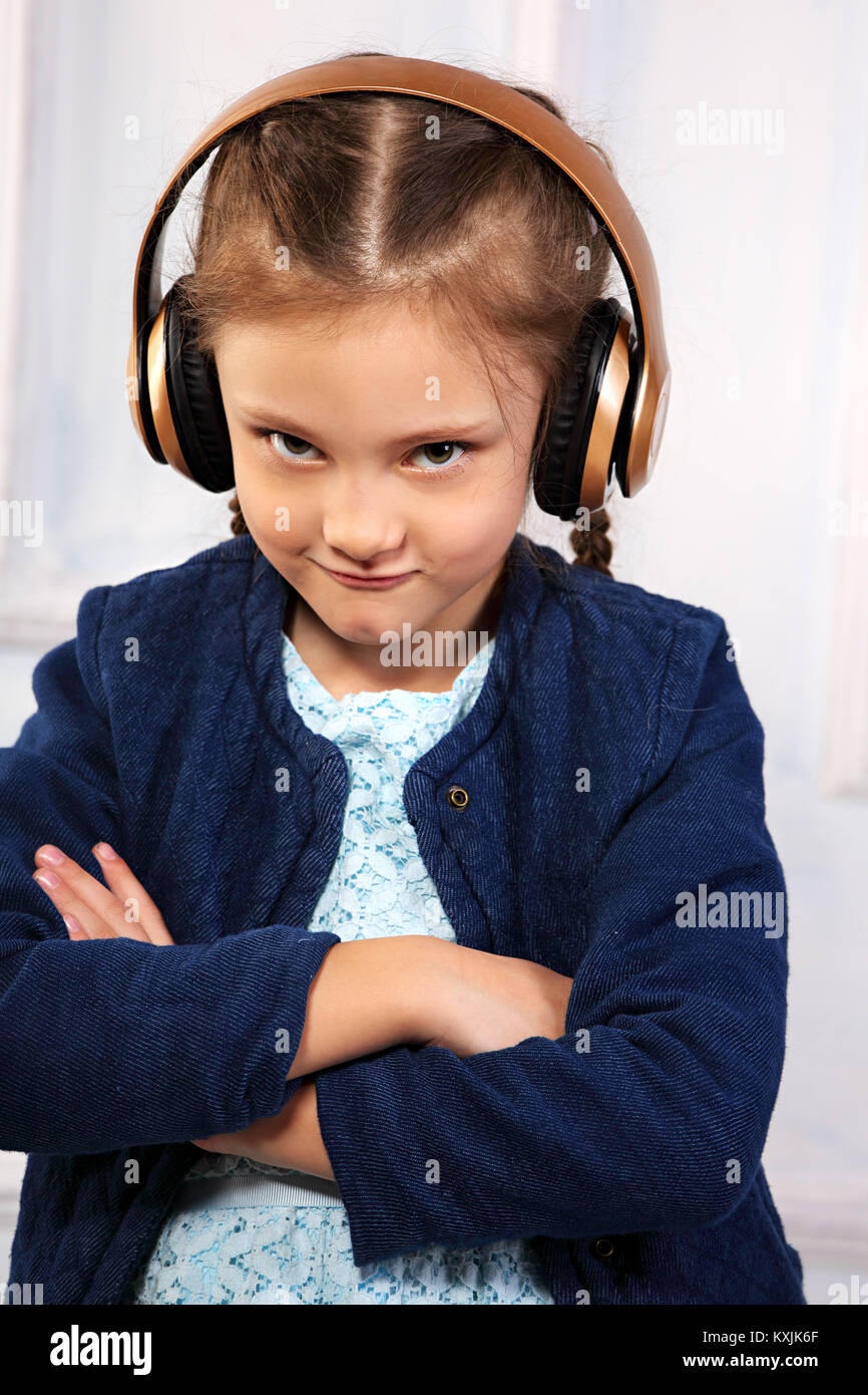 Angry funny serious kid girl in blue jacket listening the music in ...