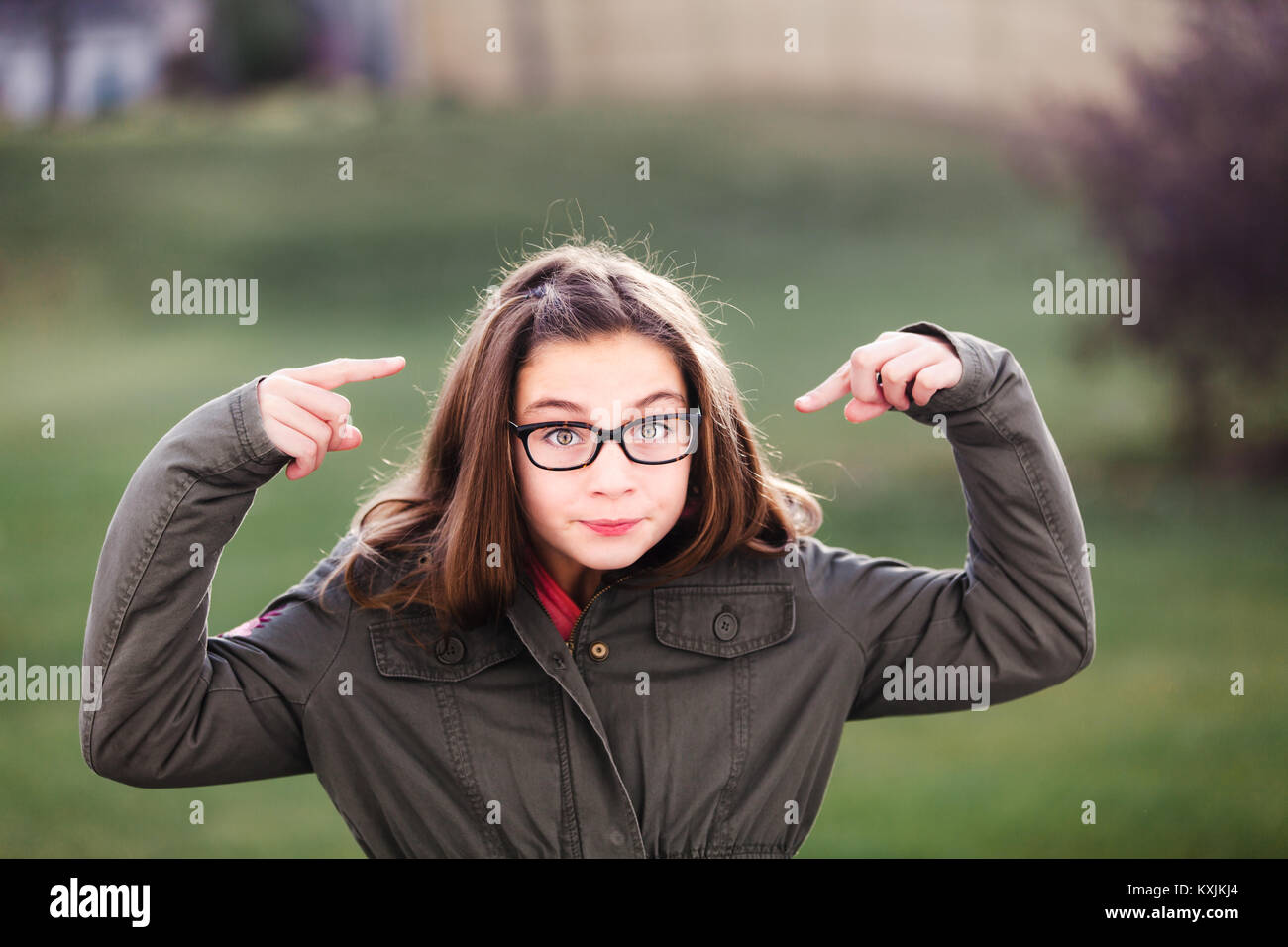 Portrait of girl in spectacles pointing at her face Stock Photo - Alamy