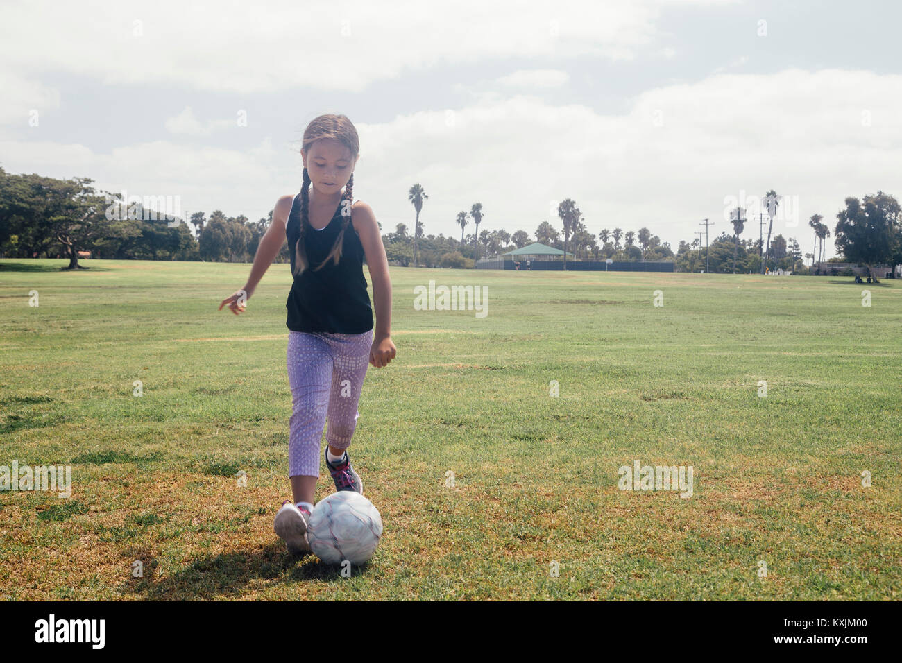 Schoolgirl kicking soccer ball on school sports field Stock Photo - Alamy