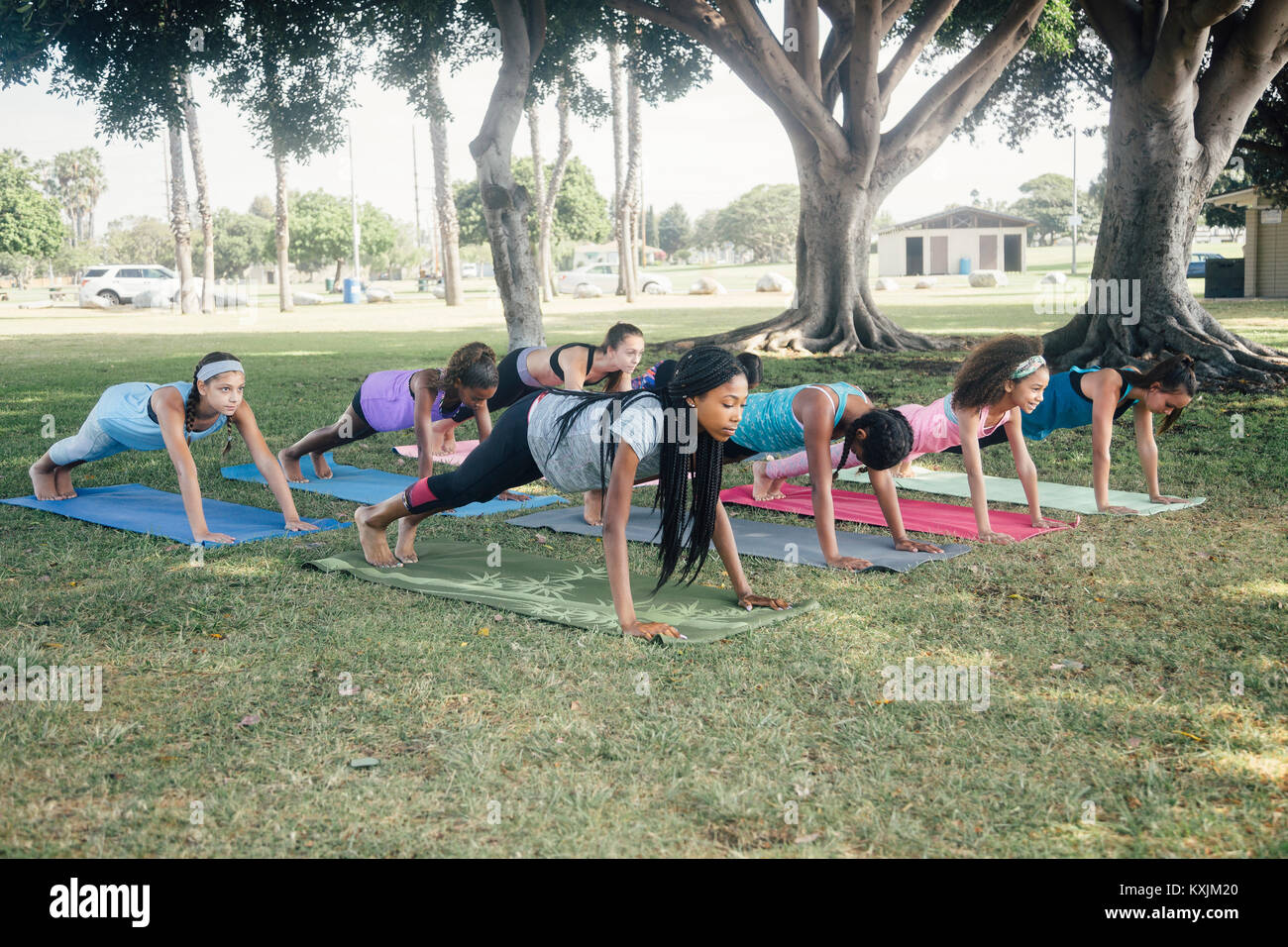 Schoolgirls practicing yoga plank pose on school sports field Stock ...