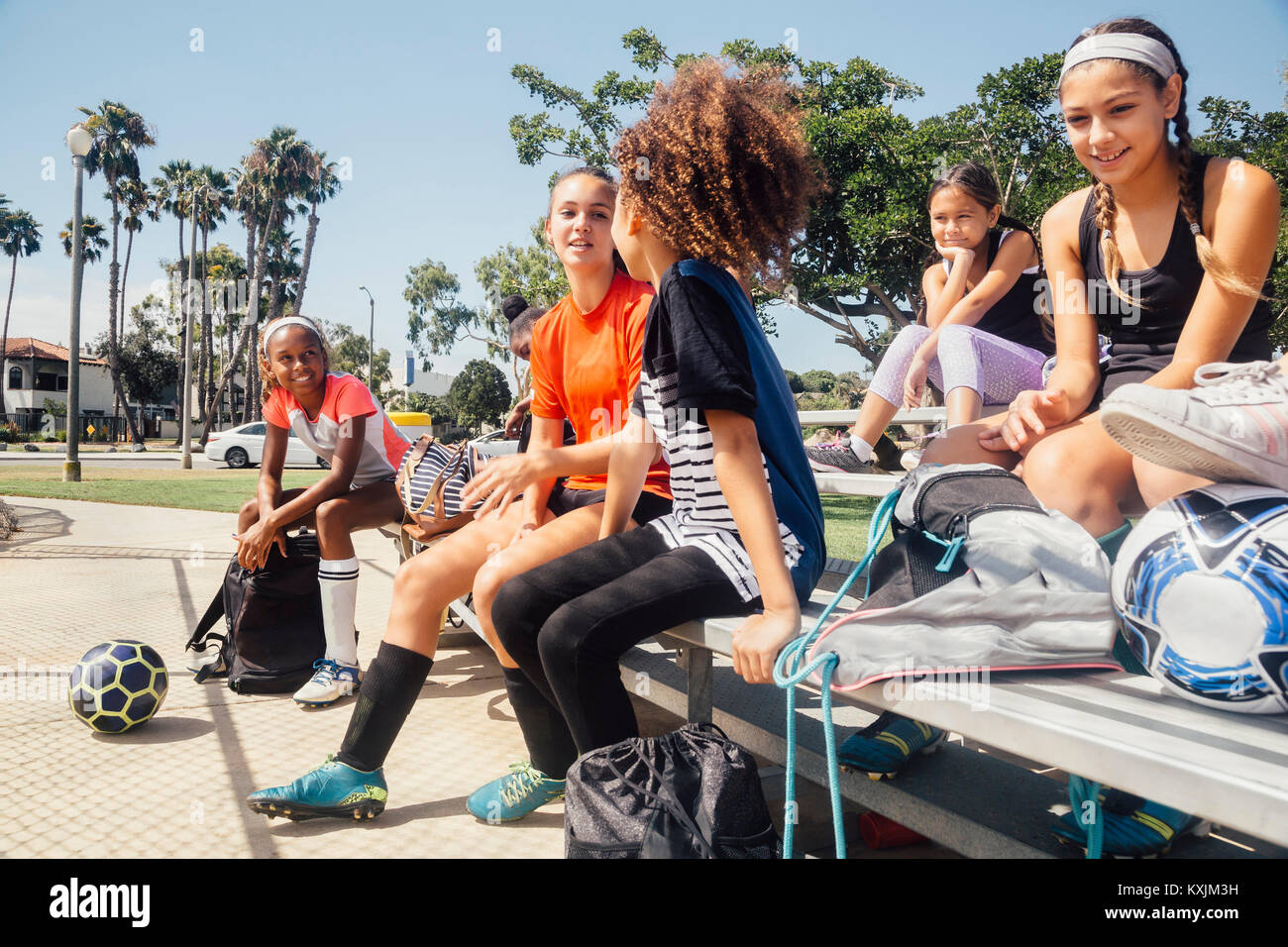 Schoolgirl soccer players chatting on school sports field bench Stock ...