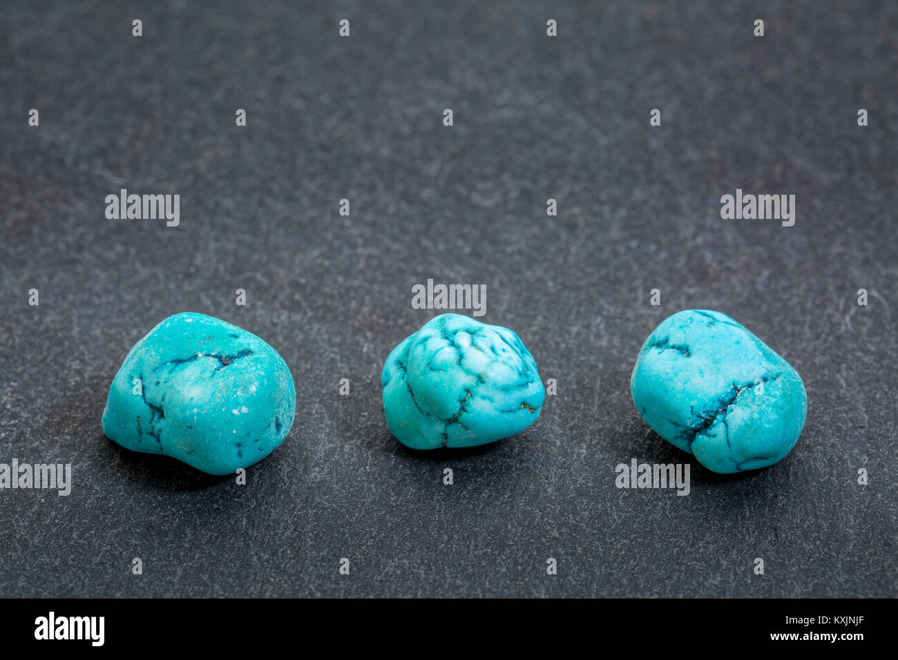 a row of blue turquenite gemstones on a gray slate stone background ...