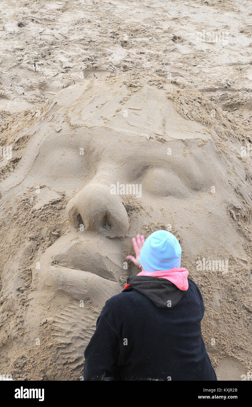 a sand sculptor or artist carving models and shapes out of the sand on ...