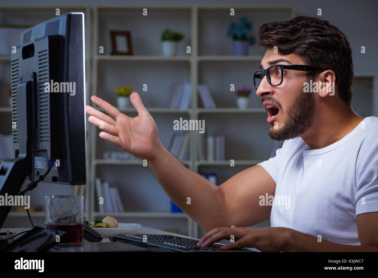 Young man staying late in office to do overtime work Stock Photo - Alamy