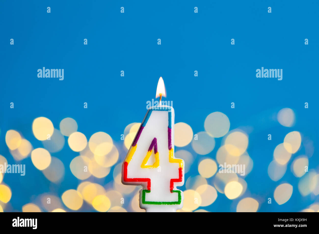 Number 4 birthday celebration candle against a bright lights and blue ...