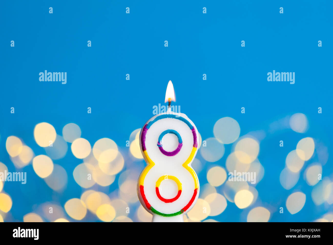 Number 8 birthday celebration candle against a bright lights and blue ...
