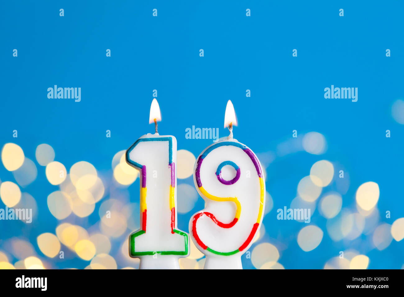 Number 19 birthday celebration candle against a bright lights and blue ...
