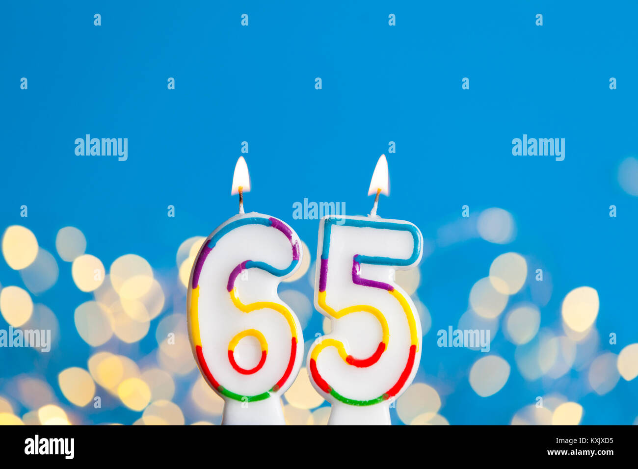 Number 65 birthday celebration candle against a bright lights and blue ...