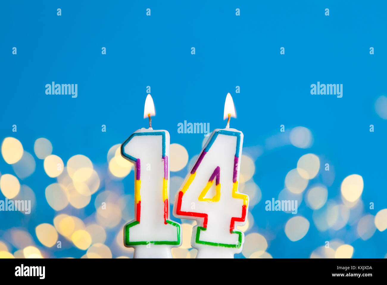 Number 14 birthday celebration candle against a bright lights and blue ...