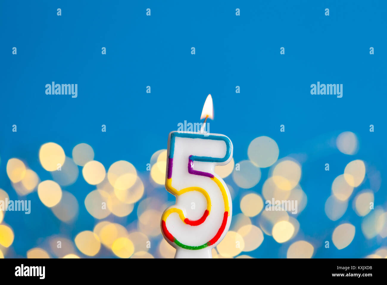 Number 5 birthday celebration candle against a bright lights and blue ...