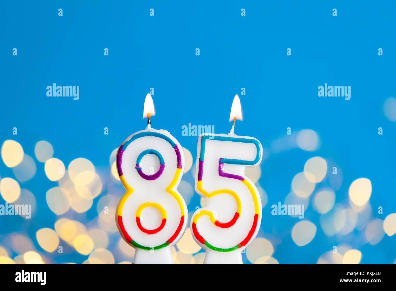 Number 85 birthday celebration candle against a bright lights and blue ...