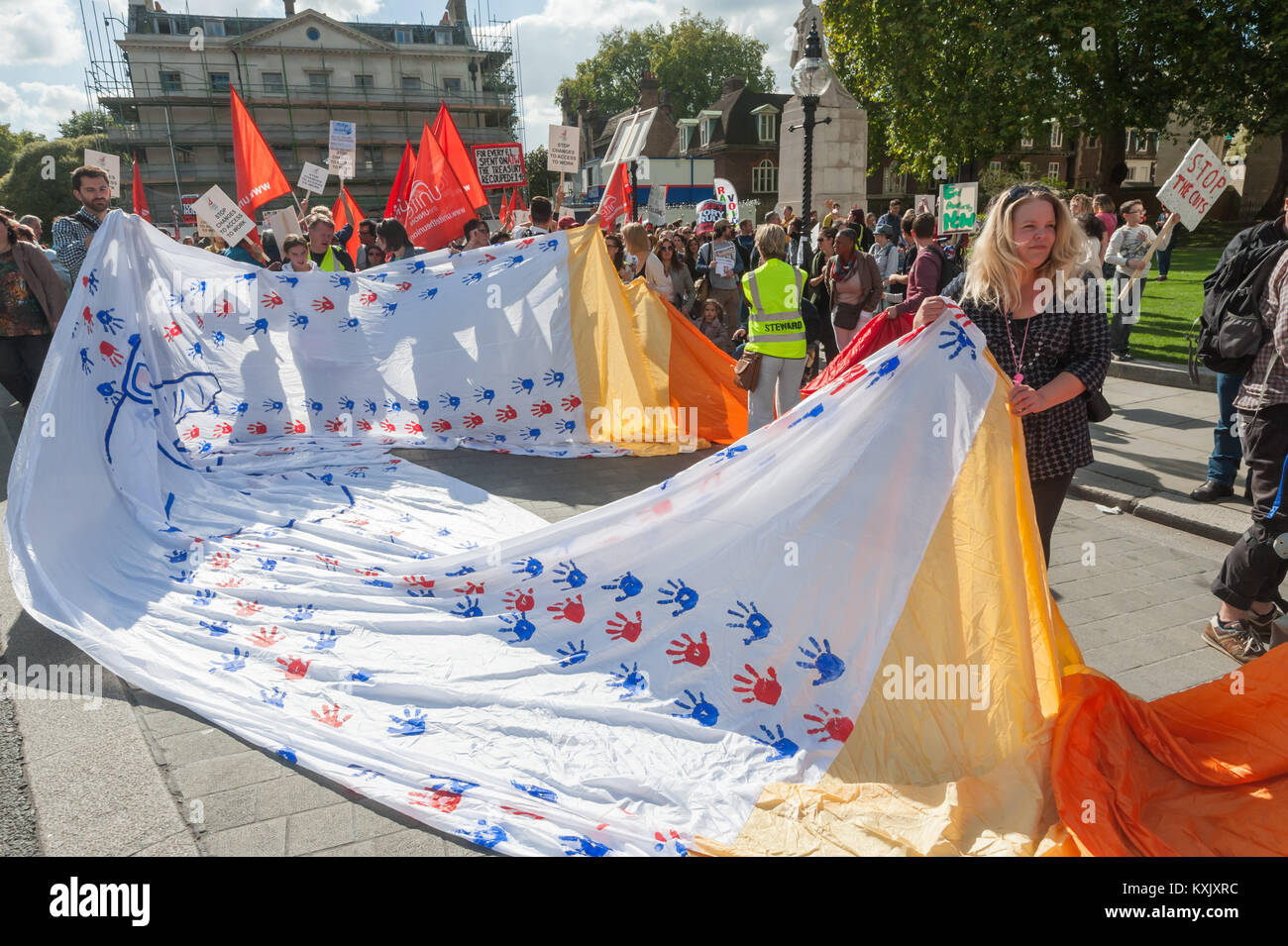 Protesters cast shadows on a large banner with many hands on it ...