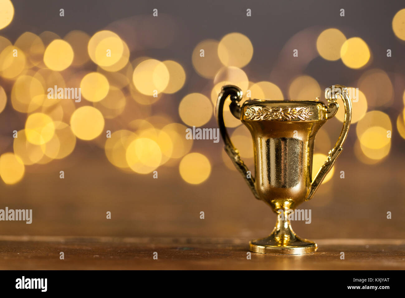 Gold award trophy against bright blurred lights Stock Photo - Alamy
