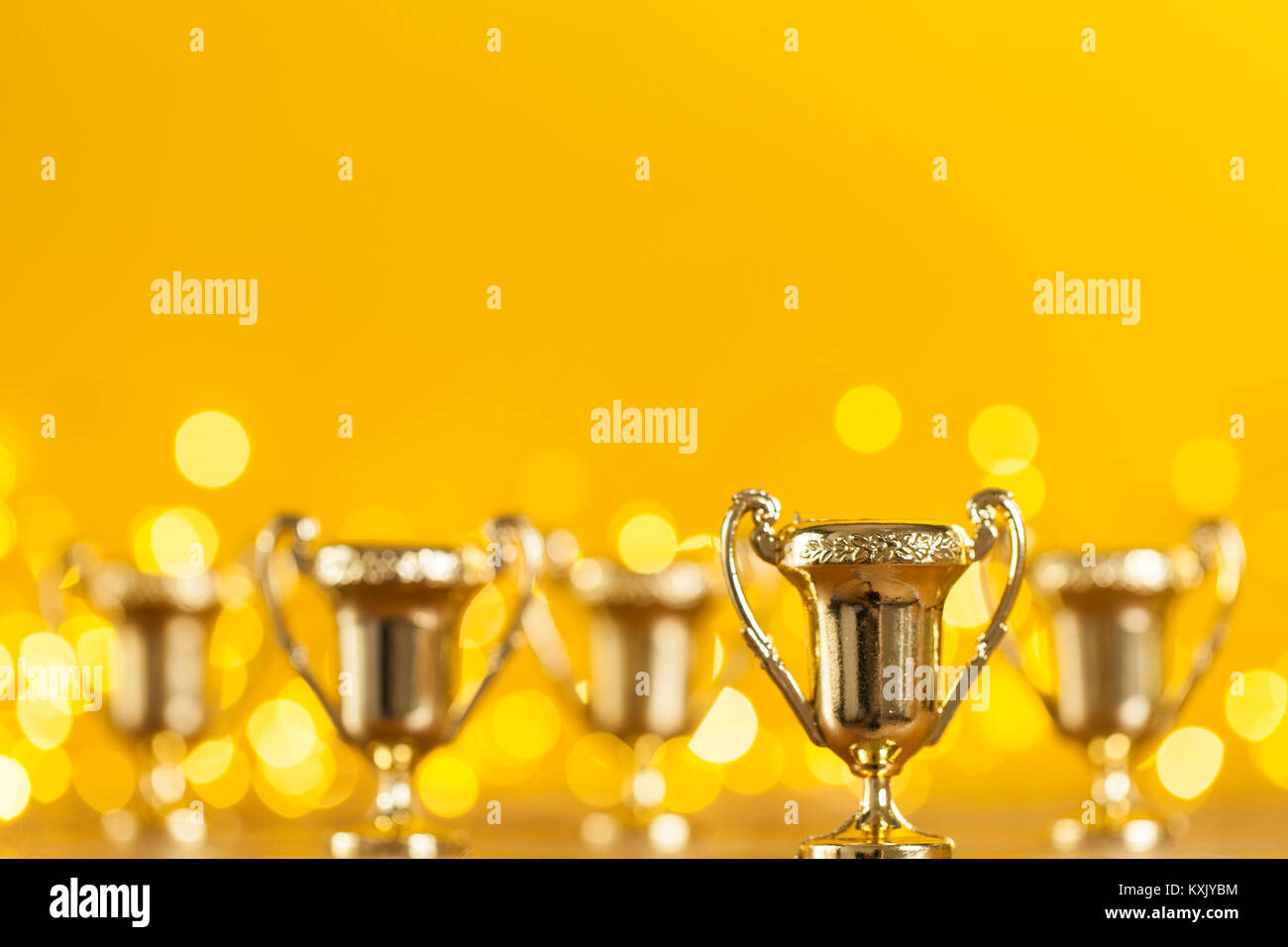 Gold award trophy against bright yellow background with blurred lights ...