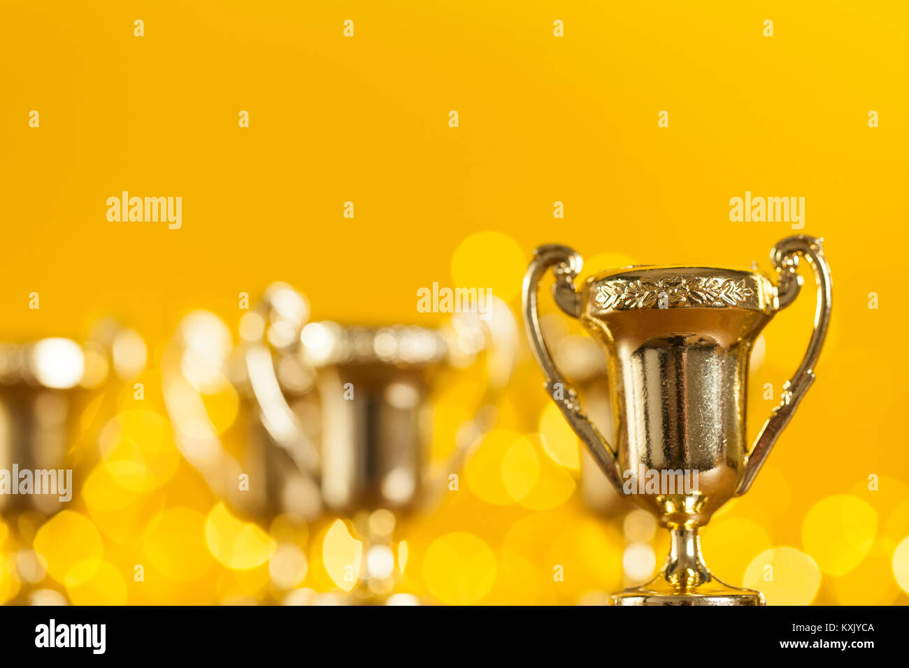 Gold award trophy against bright yellow background with blurred lights ...