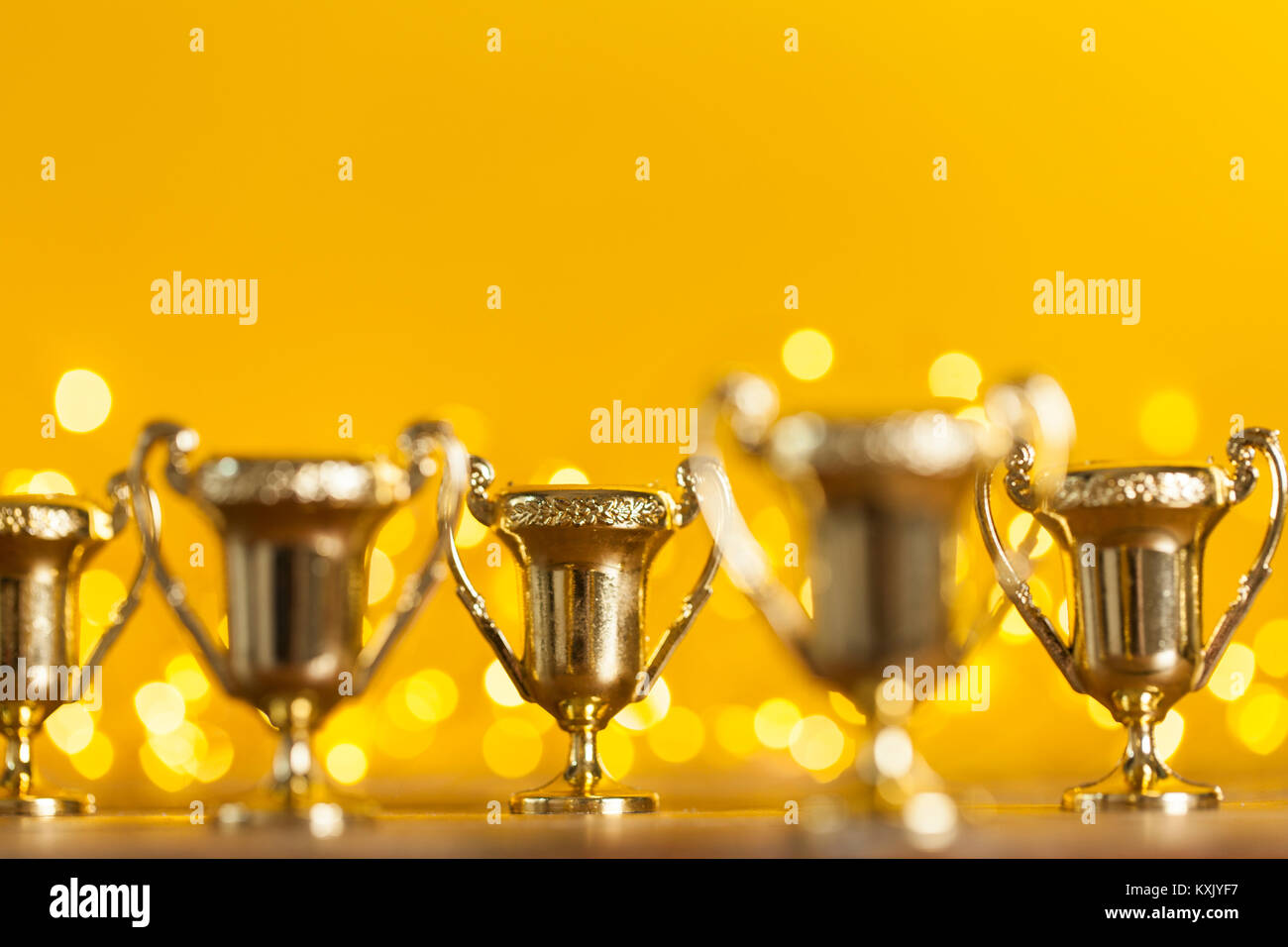 Gold award trophy against bright yellow background with blurred lights ...