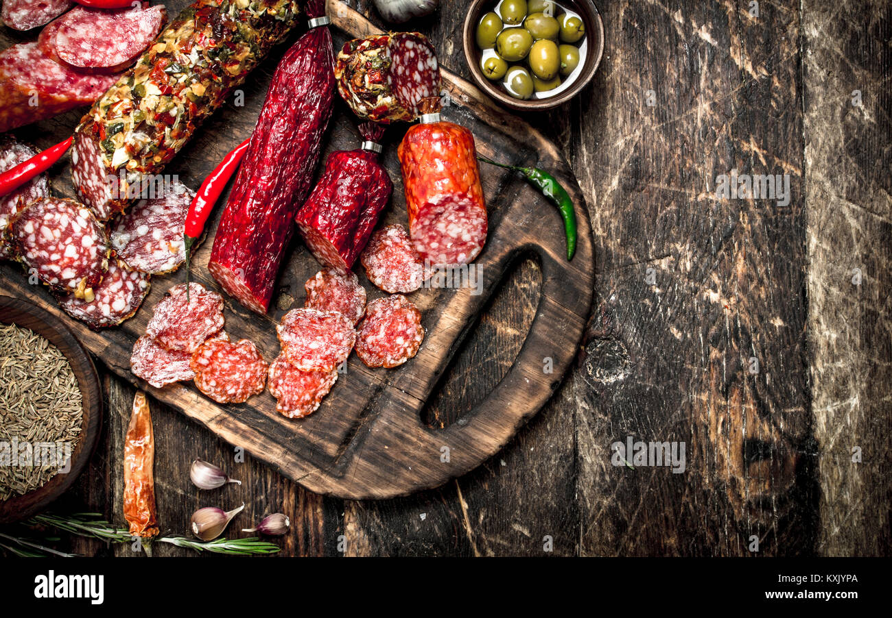 Different kinds of salami on the boards. On a wooden background Stock ...
