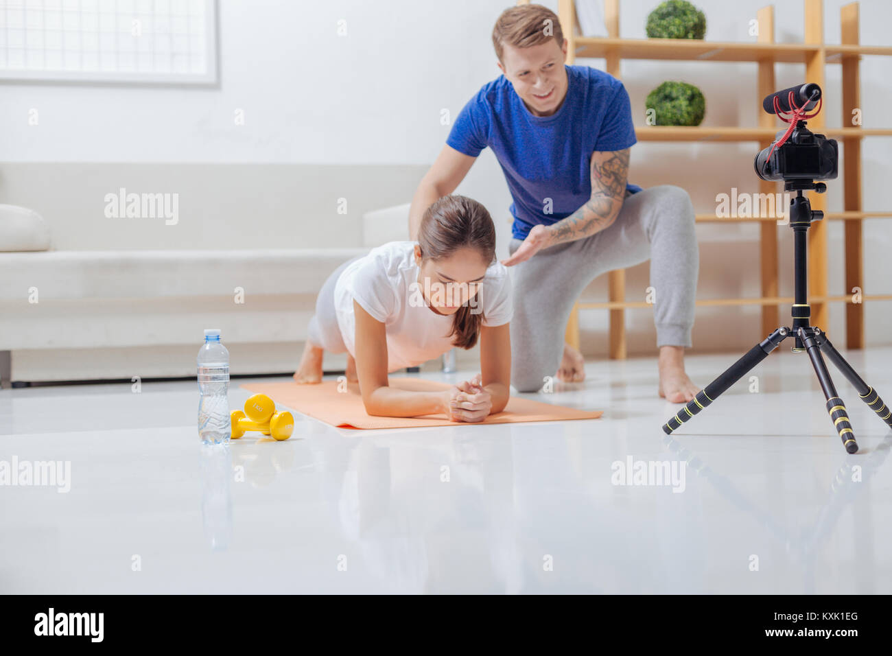 Positive man showing healthy exercises together with his assistant ...