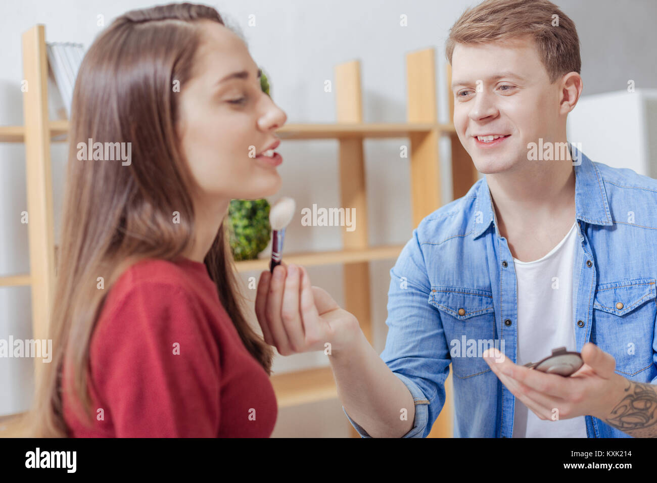 Attentive man touching his colleague with a soft brush and smiling ...