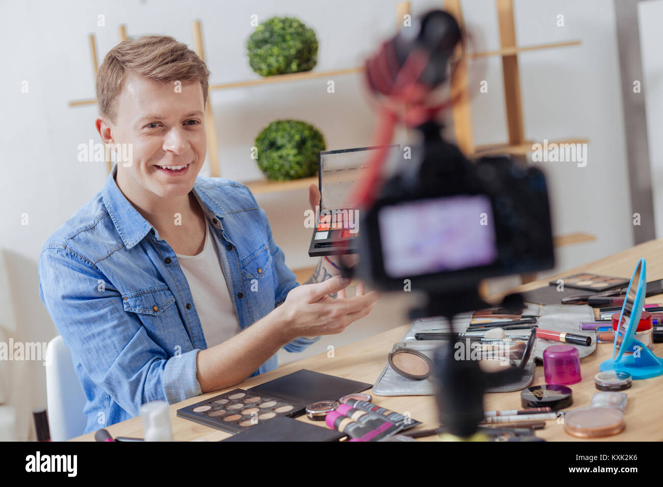 Attractive man smiling while showing a shadow palette Stock Photo - Alamy