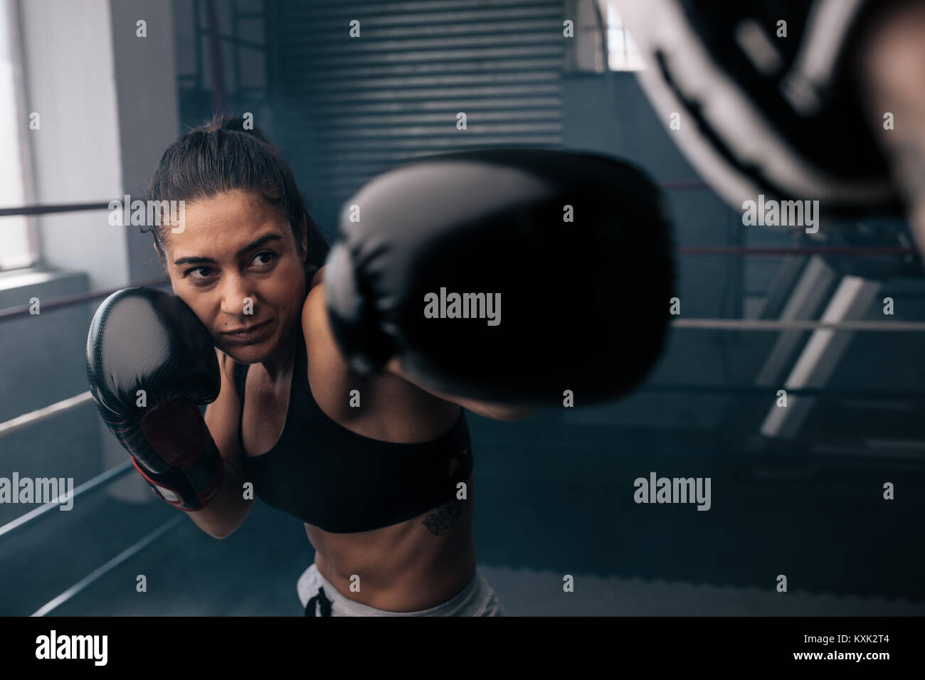 Boxer practicing her punches at a boxing studio. Close up of a female ...