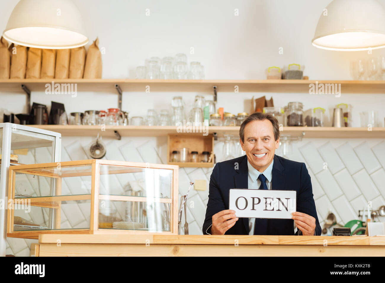 Busy satisfied owner standing in his shop and smiling Stock Photo - Alamy