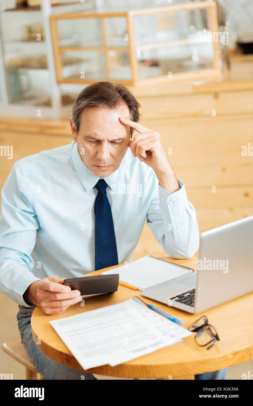Deep thoughtful man making calculations and using the laptop Stock ...