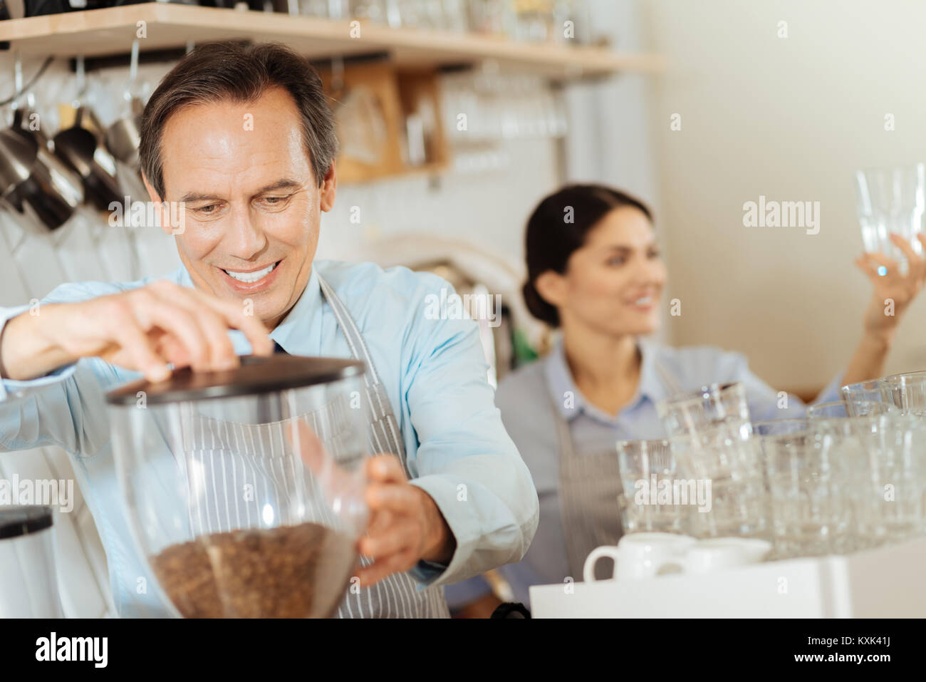 Interested responsible man standing and making coffee Stock Photo - Alamy