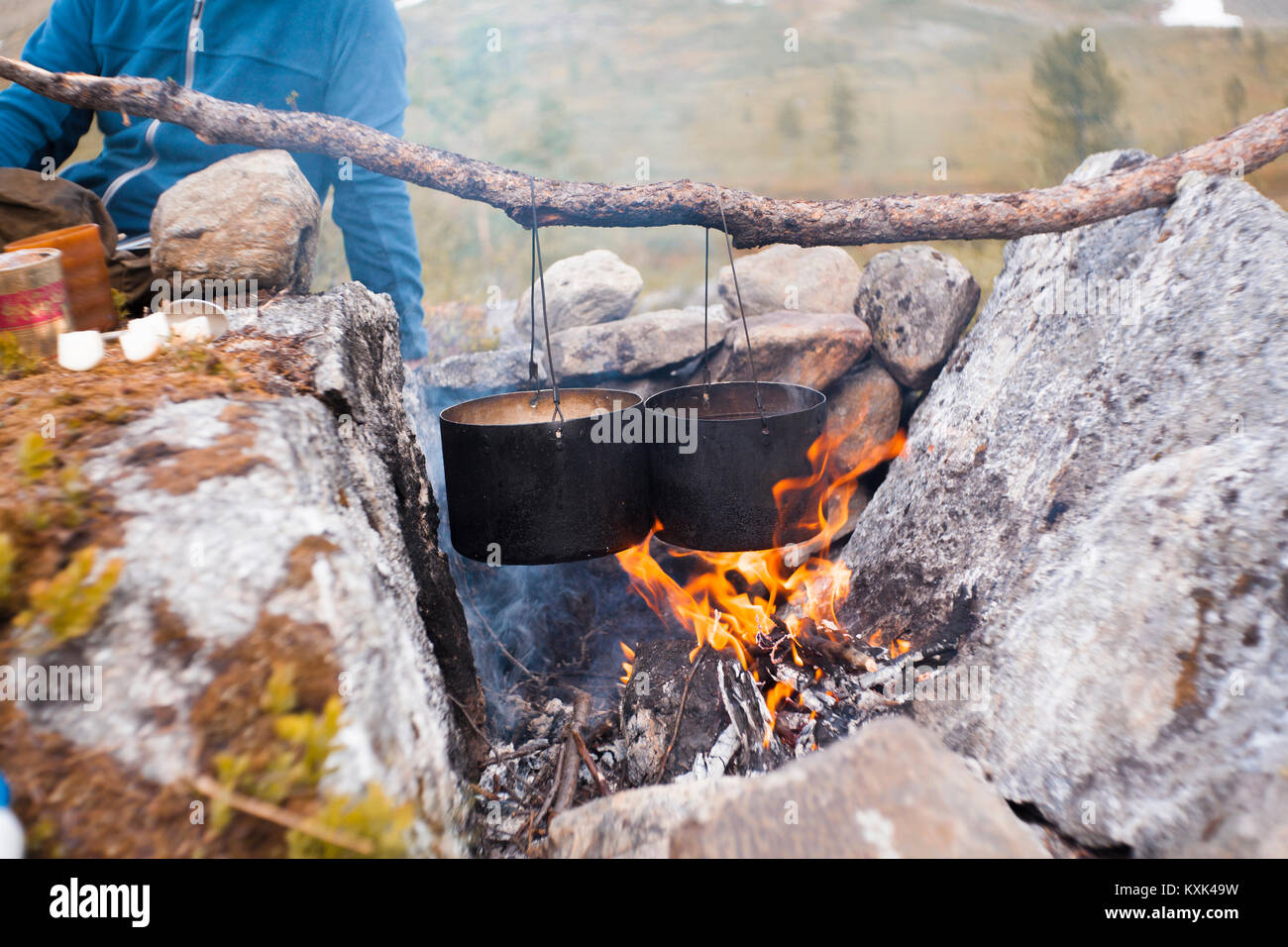 Close-up of containers hanging on wood over campfire against man Stock ...