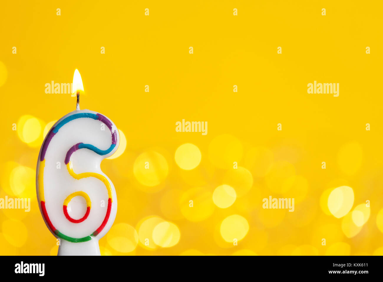 Number 6 birthday celebration candle against a bright lights and yellow ...