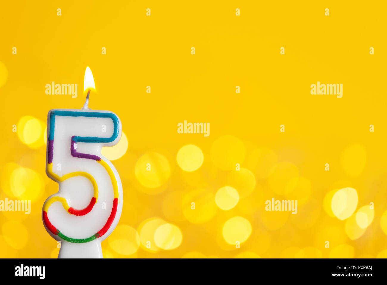 Number 5 birthday celebration candle against a bright lights and yellow ...