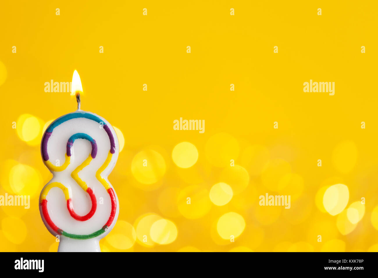 Number 3 birthday celebration candle against a bright lights and yellow ...