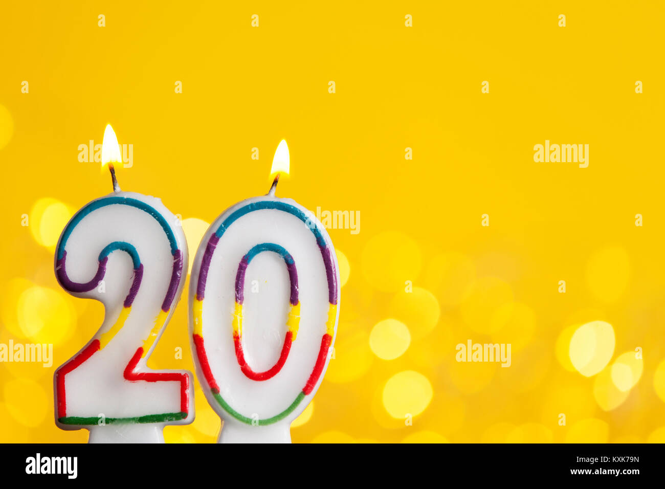 Number 20 birthday celebration candle against a bright lights and ...
