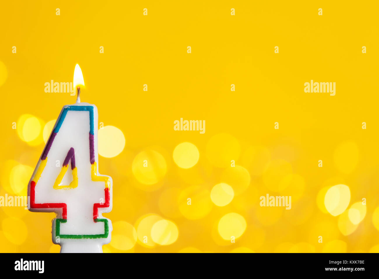 Number 4 birthday celebration candle against a bright lights and yellow ...
