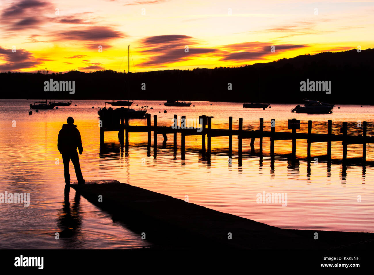 A man watches the sunset at Waterhead, in Ambleside over Lake ...